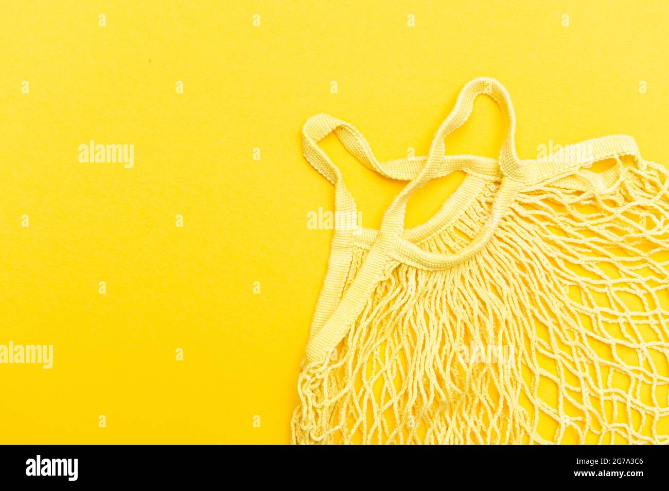 Empty mesh bag for shopping on a yellow background isolated. Zero waste ...