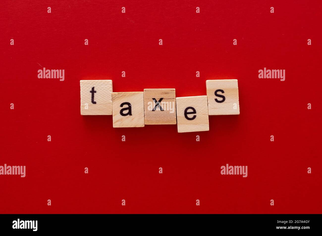 word TAXES made of wooden letters on red background with copy space ...