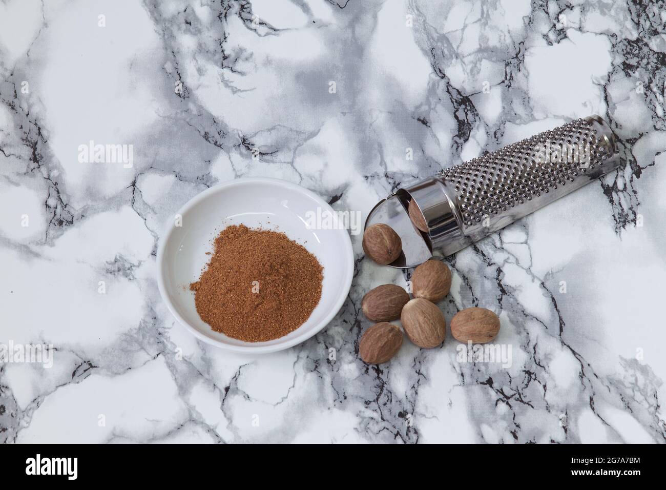 Whole nutmegs and some grated nutmeg in a dish Stock Photo - Alamy
