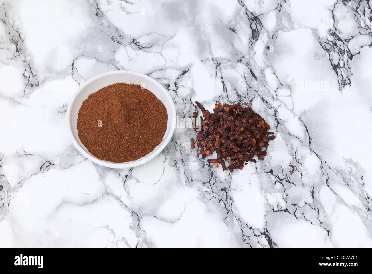 Whole cloves and ground cloves in a dish Stock Photo - Alamy