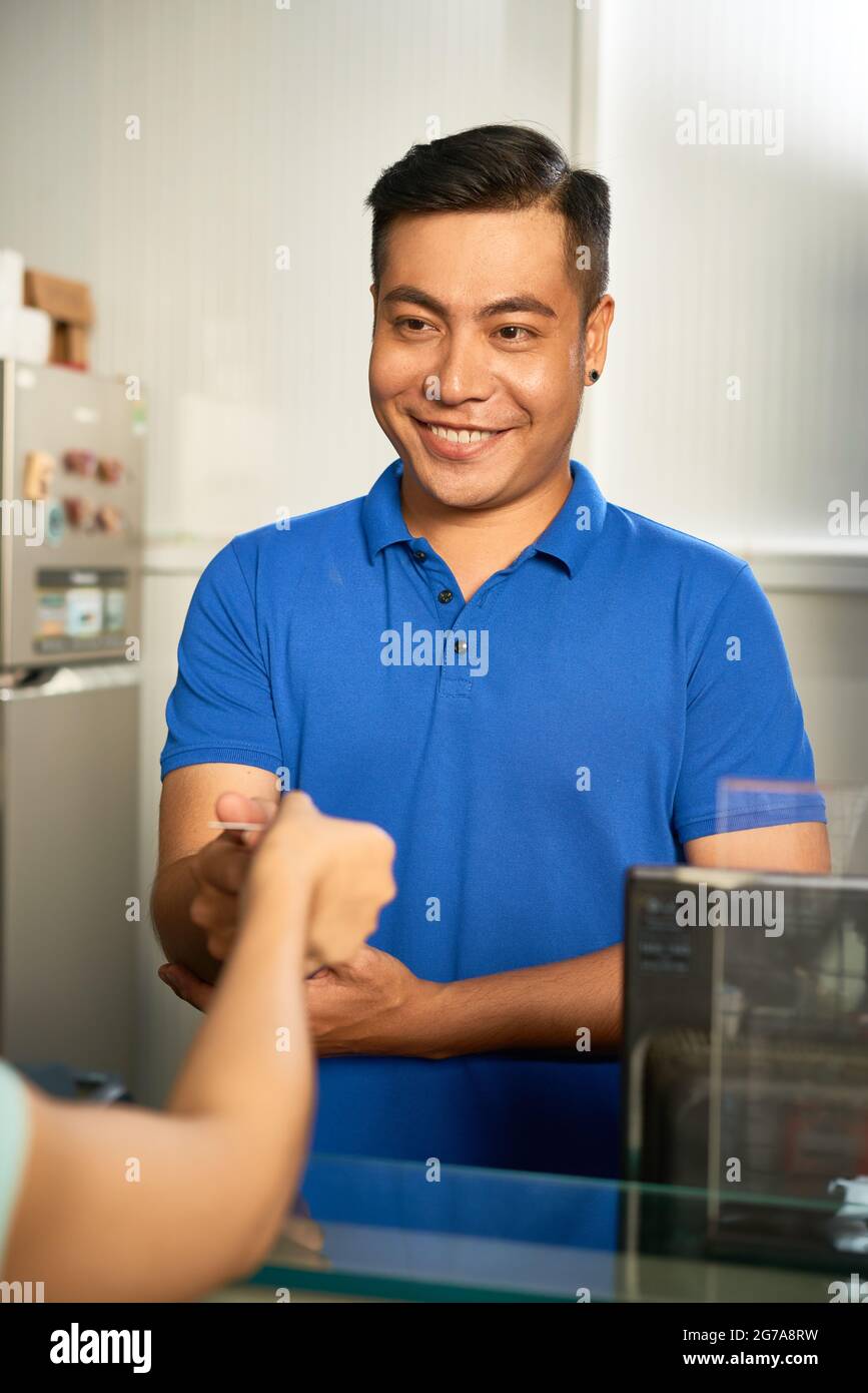 Handsome smiling cashier worker accepting payment with credit card ...