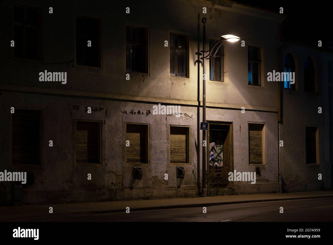 At night on the street, old uninhabited and broken apartment building ...
