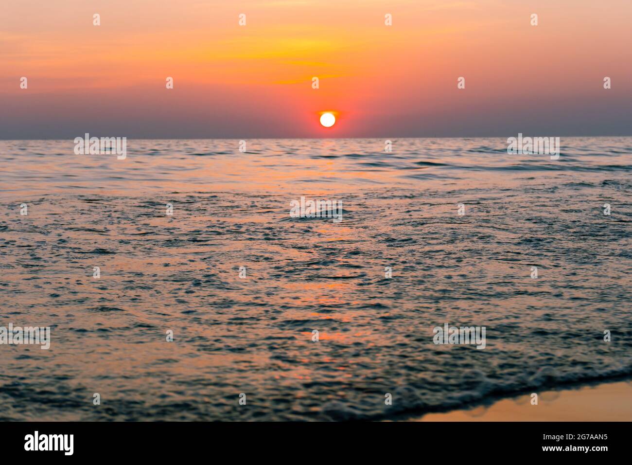 Sunset reflection sea. beautiful sunset behind the clouds and blue sky ...