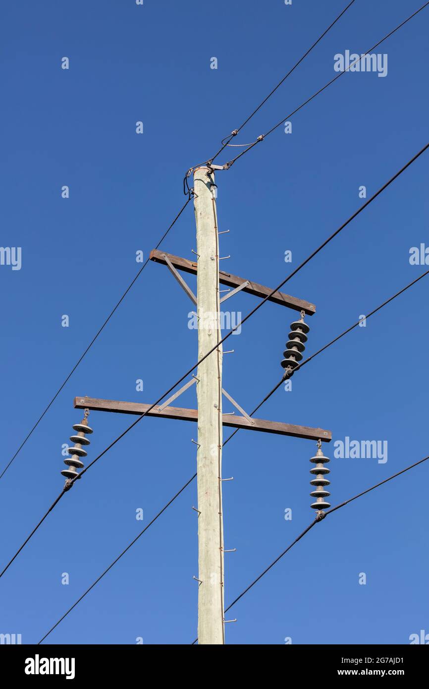 Photograph of a wooden telephone post and cables against a blue sky ...