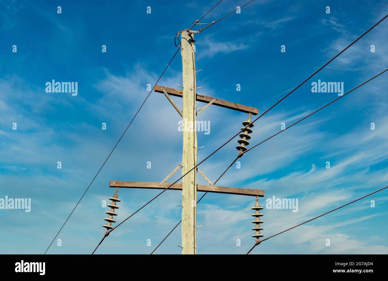 Photograph of a wooden telephone post and cables against a blue sky ...