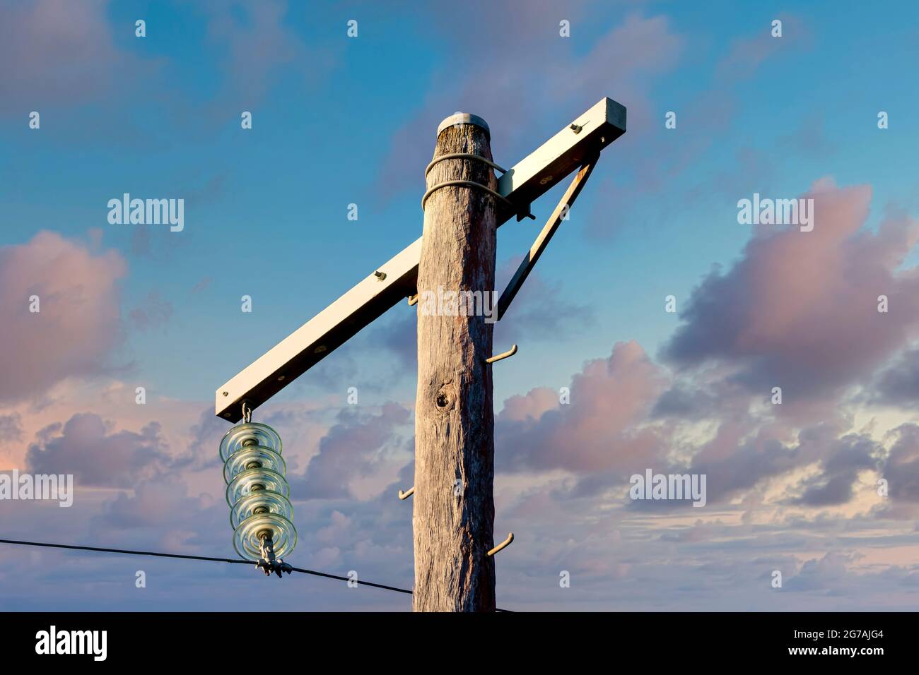 Photograph of a wooden telephone post and cables against a blue sky ...