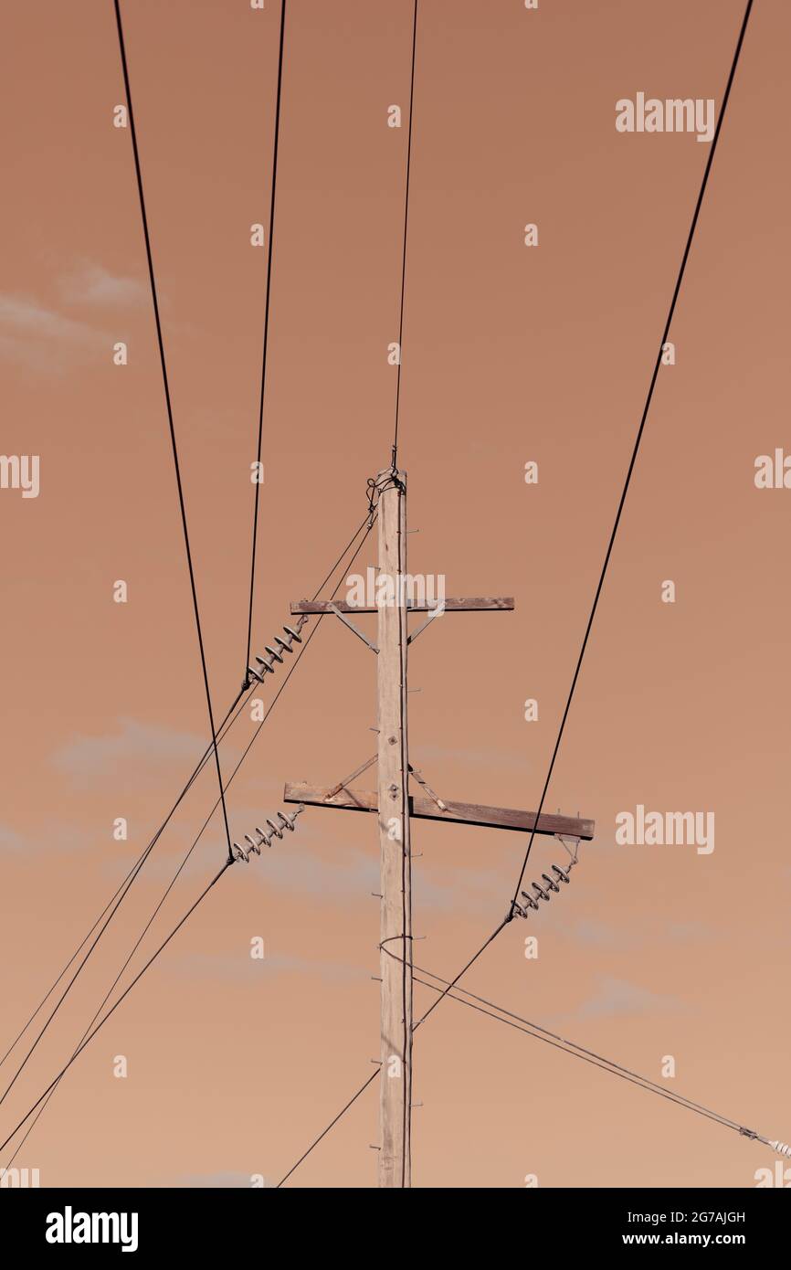 Photograph of a wooden telephone post and cables against a blue sky ...