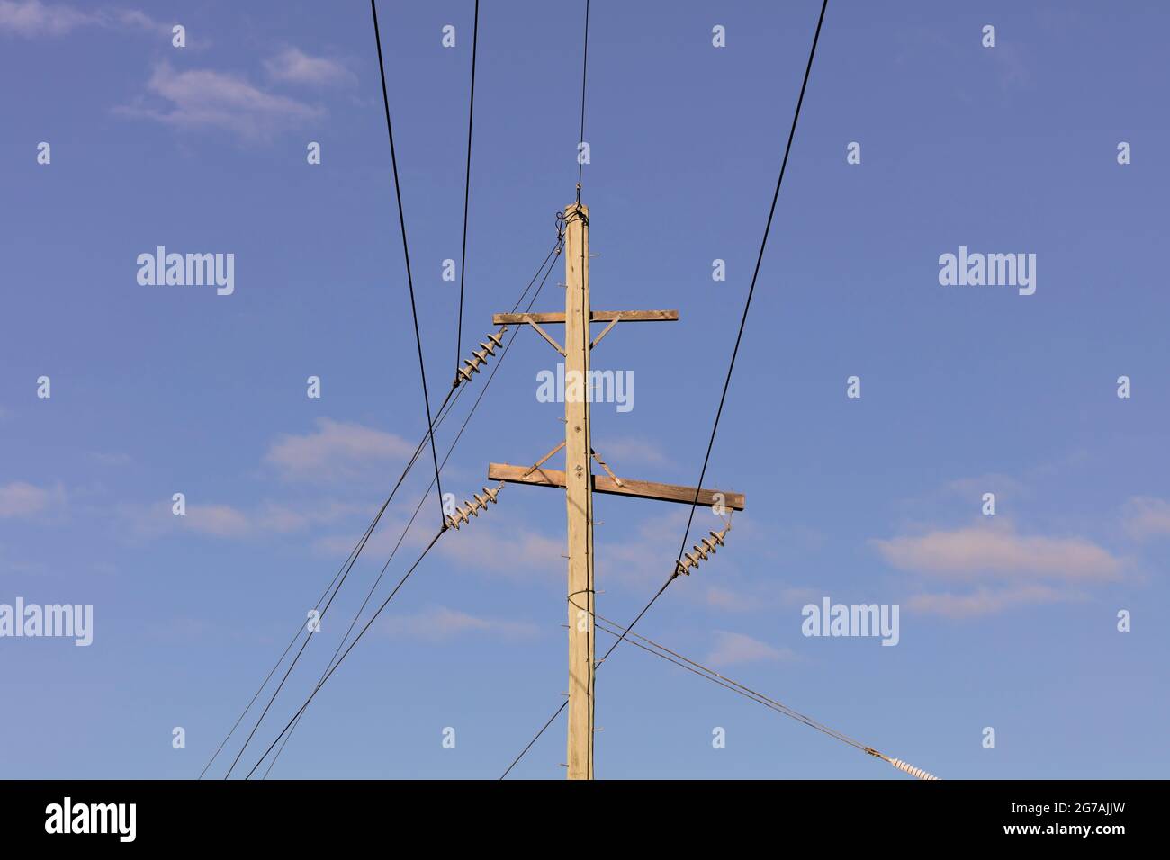 Photograph of a wooden telephone post and cables against a blue sky ...