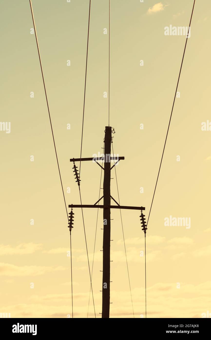 Photograph of a wooden telephone post and cables against a blue sky ...