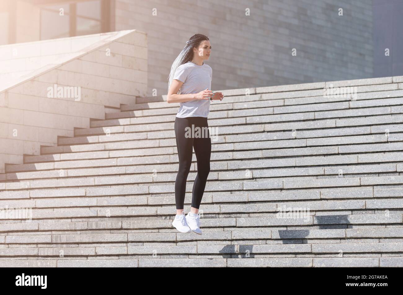 Fitness girl jumping on stairs during her morning workout. Urban sport ...