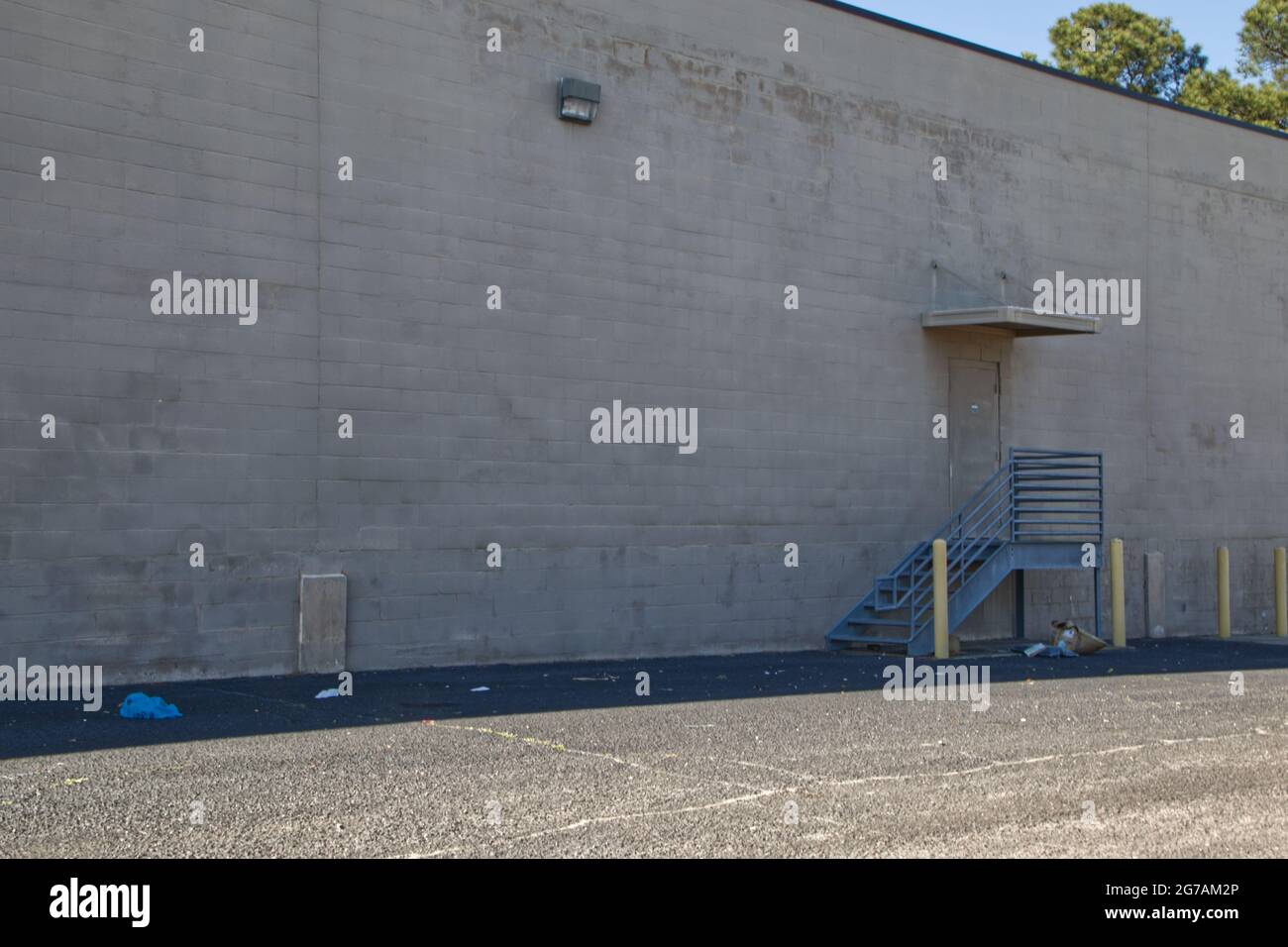Trash and waster litter on the side of a building with metal steps and ...