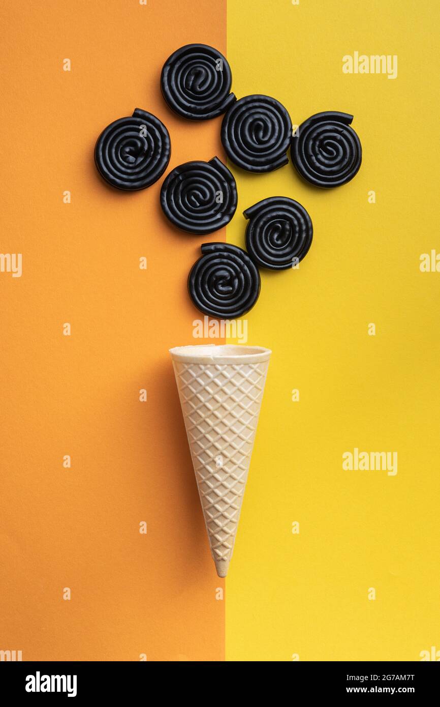 Spiral from liquorice candy and ice cream cone on colorful background ...