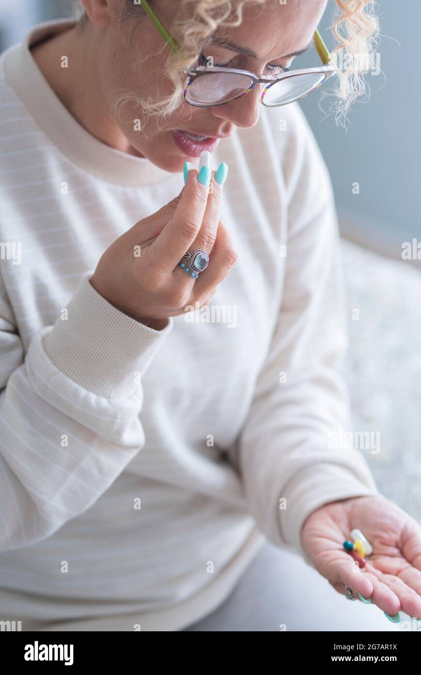 Adult woman middle age taking pills medicine at home sitting on bed ...