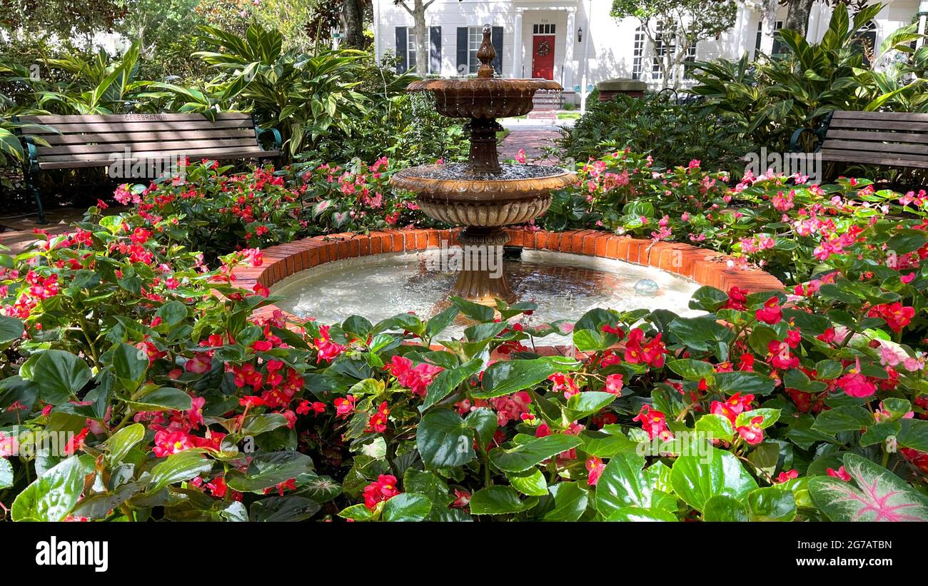 A small park with a fountain surrounded by flowers in a neighborhood in ...
