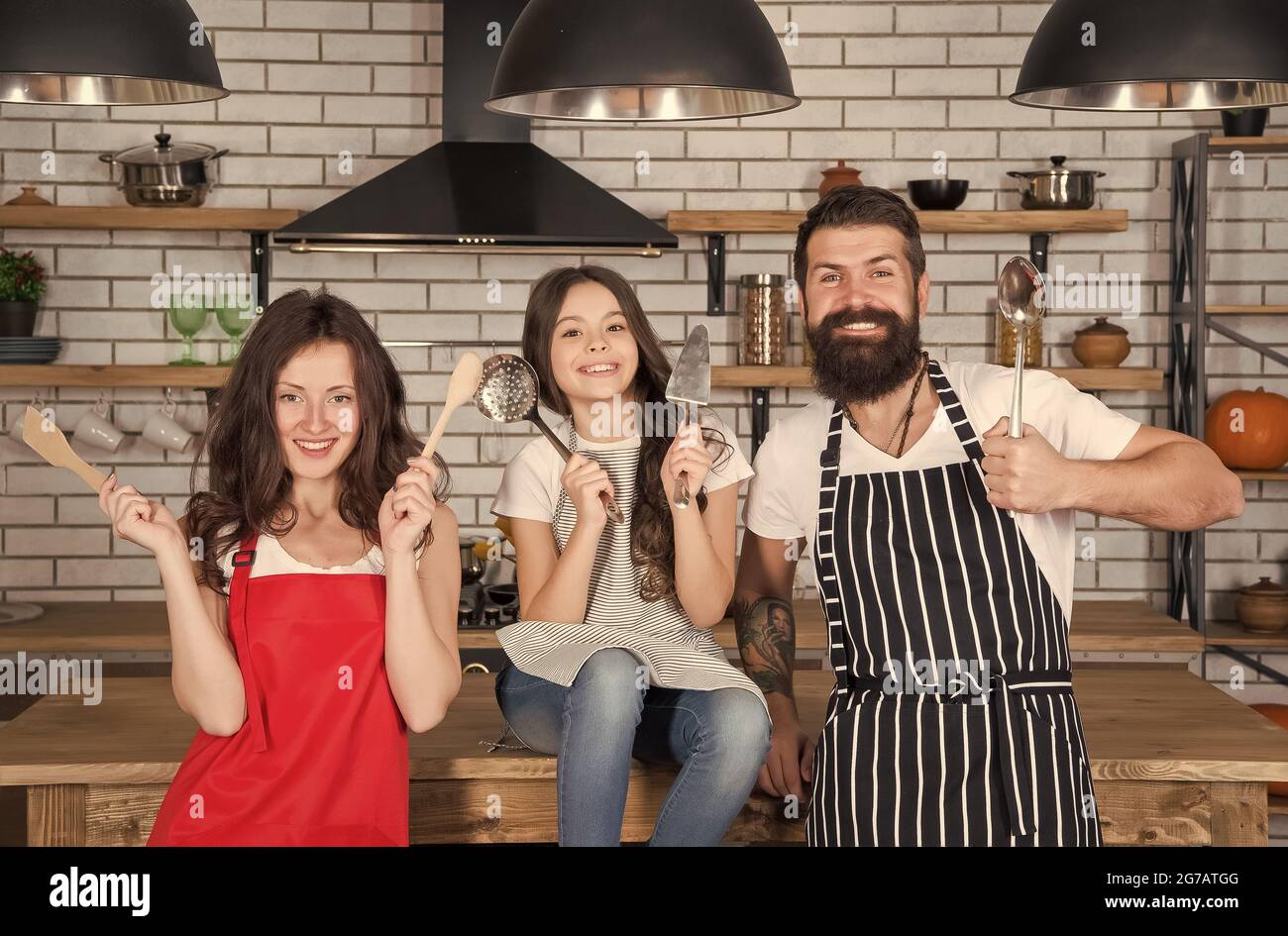father and mother with daughter cook in kitchen. little girl cooking ...