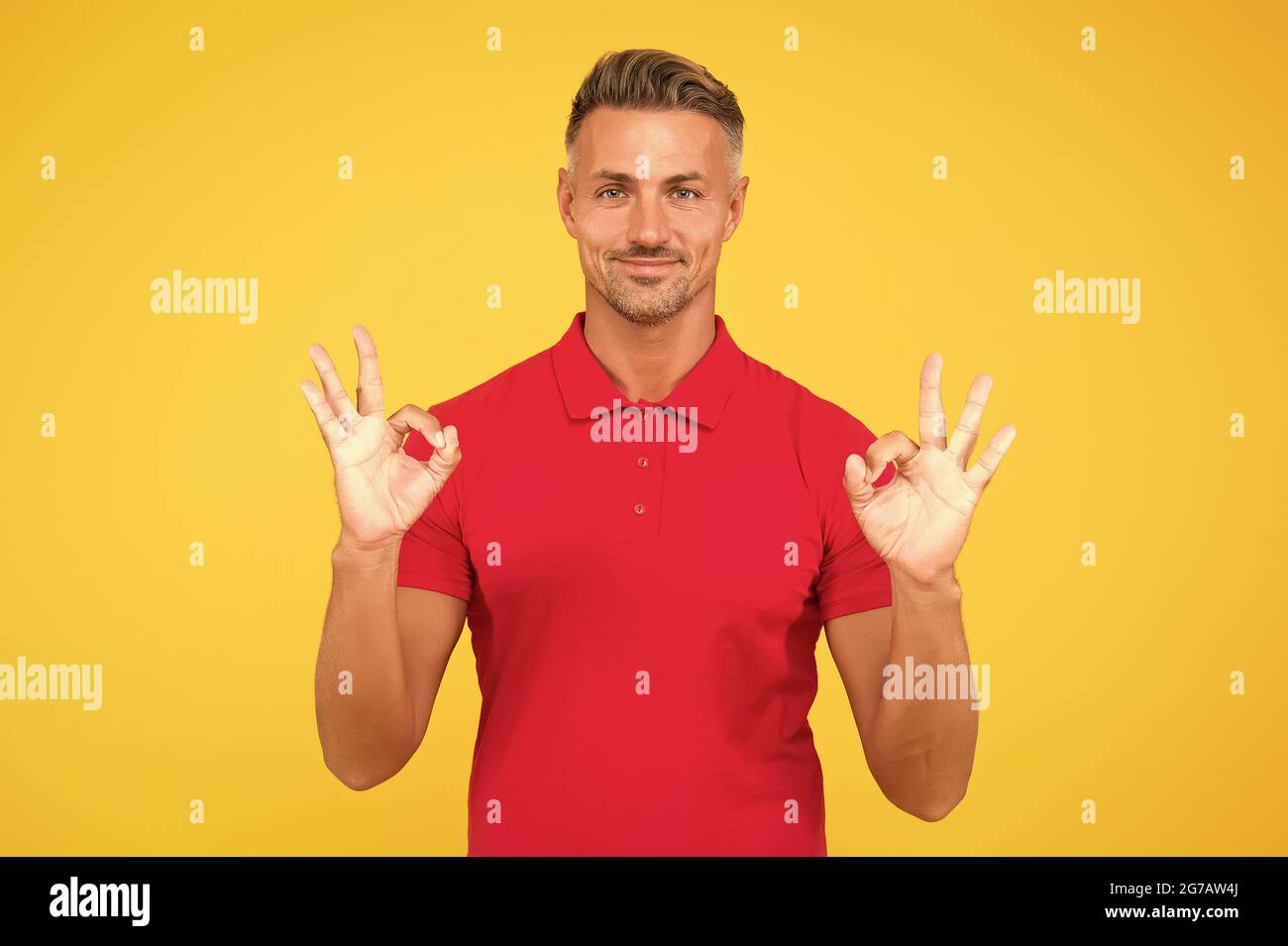 Satisfactory result. Happy man show double OK signs yellow background ...