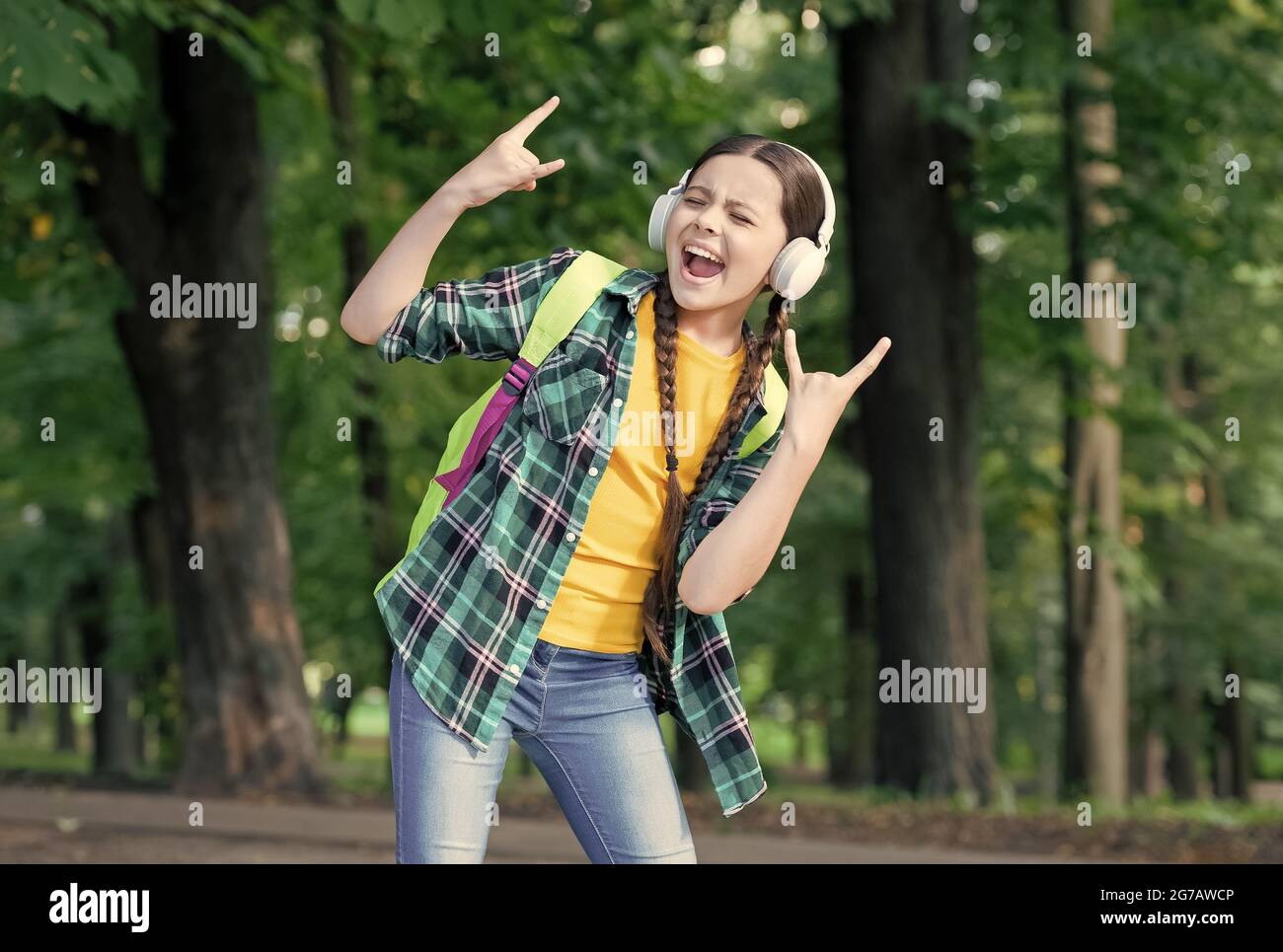 Lets rock. Happy kid make horn signs listening to music. Little girl ...