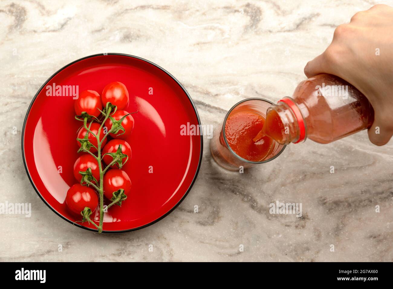 Pour tomato juice into a glass. Hand pours tomato juice from bottle ...