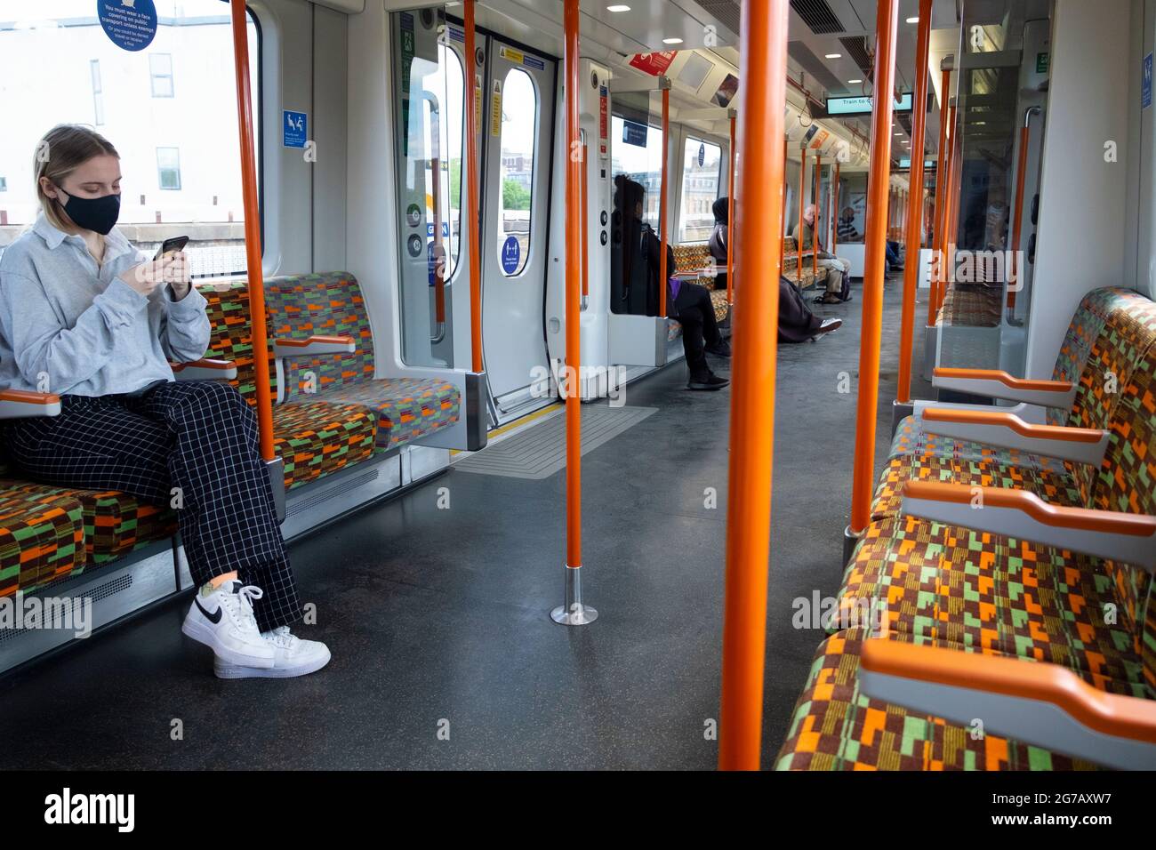 Young woman with mobile phone sitting wearing covid face mask facemask ...