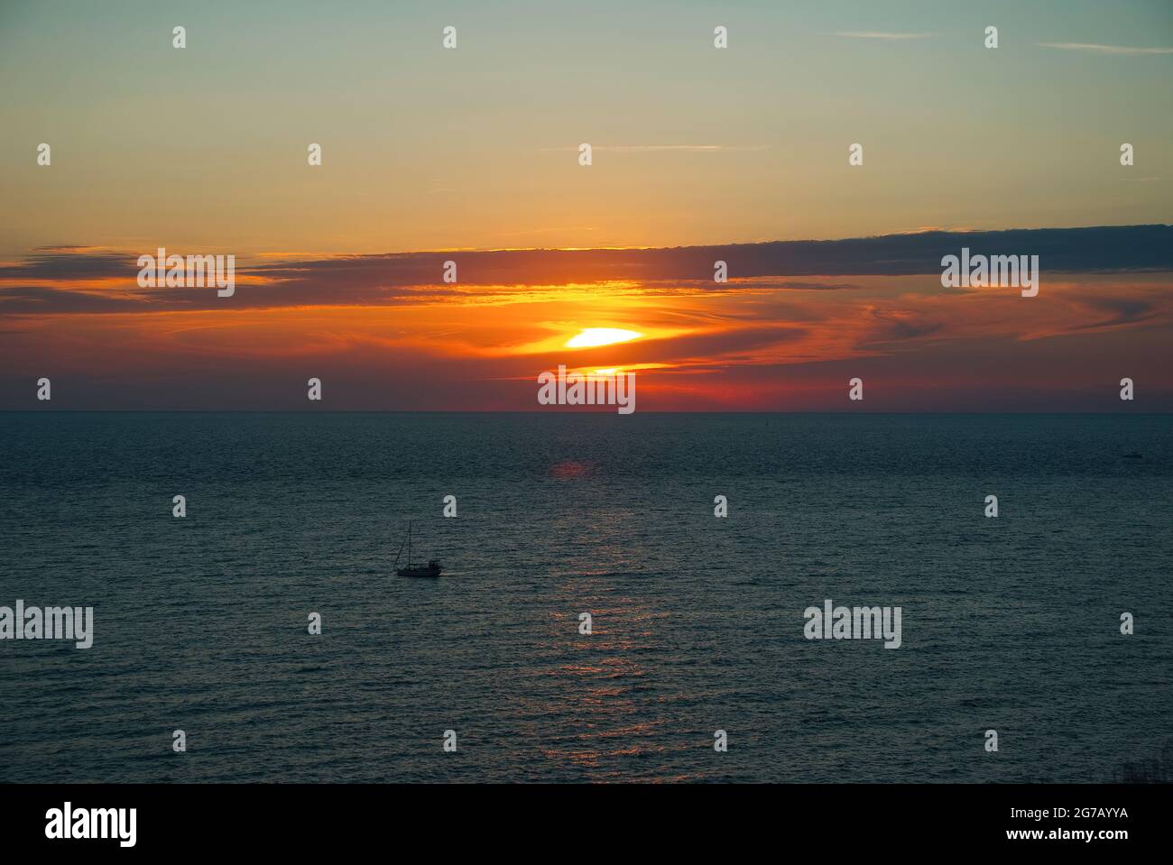 Small sailing ship at sea at sunset Stock Photo - Alamy