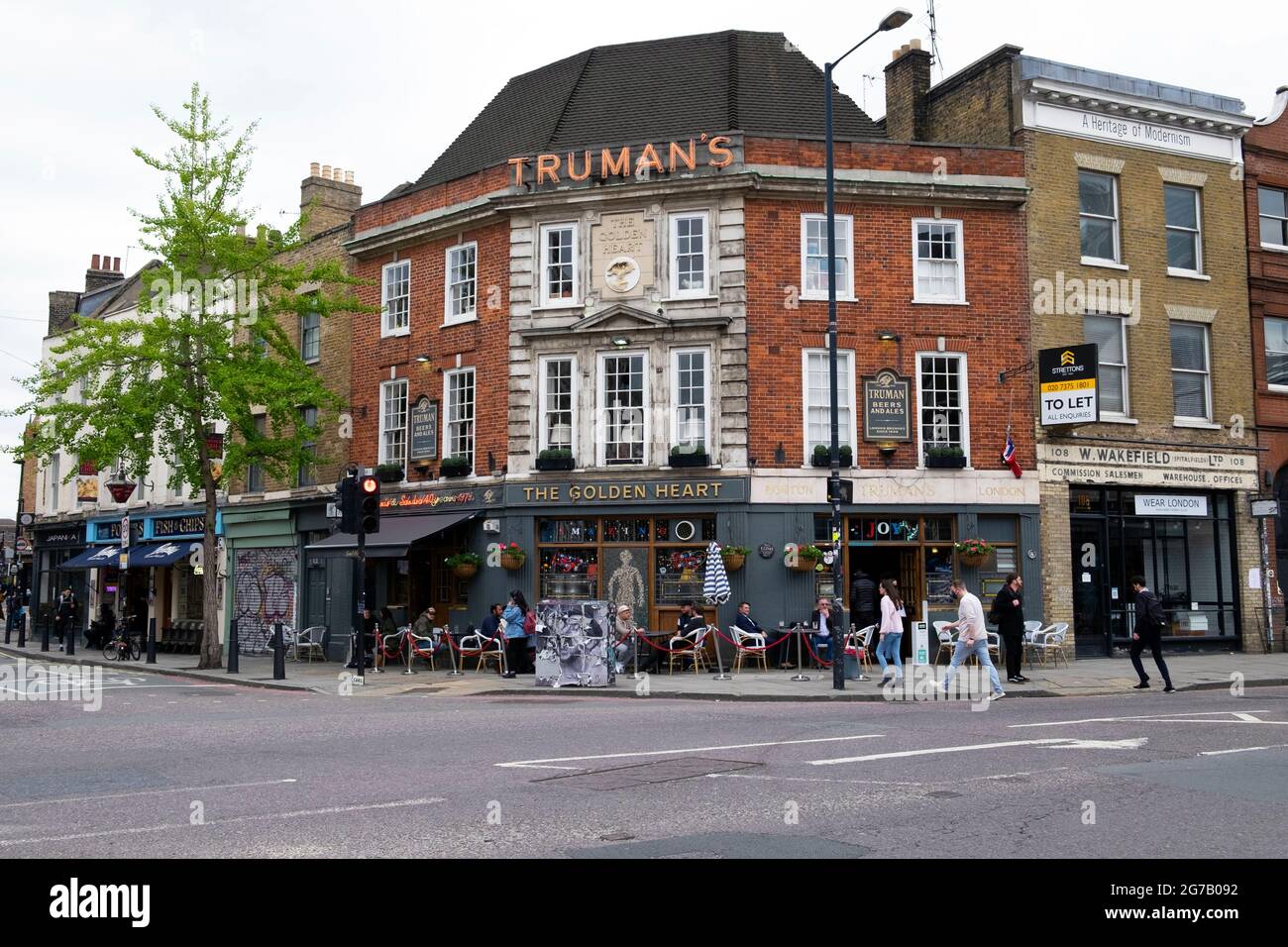 People sitting at tables social distancing outside The Golden Heart pub ...