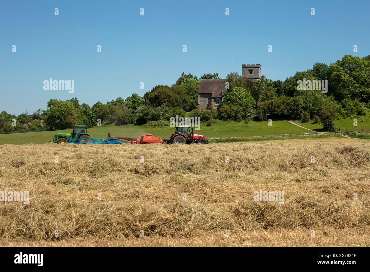 Haymaking with machines in a semi-urban farm, bright sunshine, blue sky ...