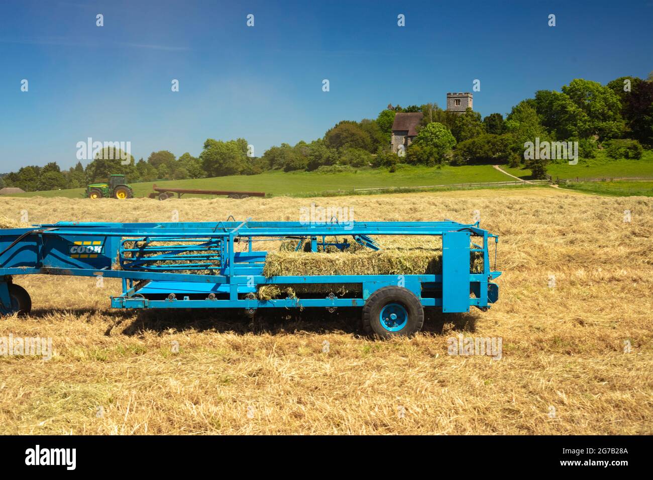 Haymaking with machines in a semi-urban farm, bright sunshine, blue sky ...