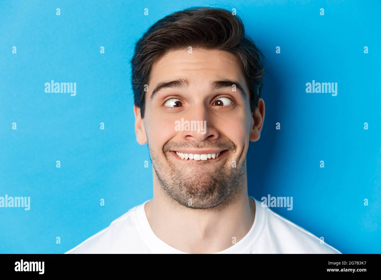 Head shot of young man making funny expressions, smiling and squinting ...
