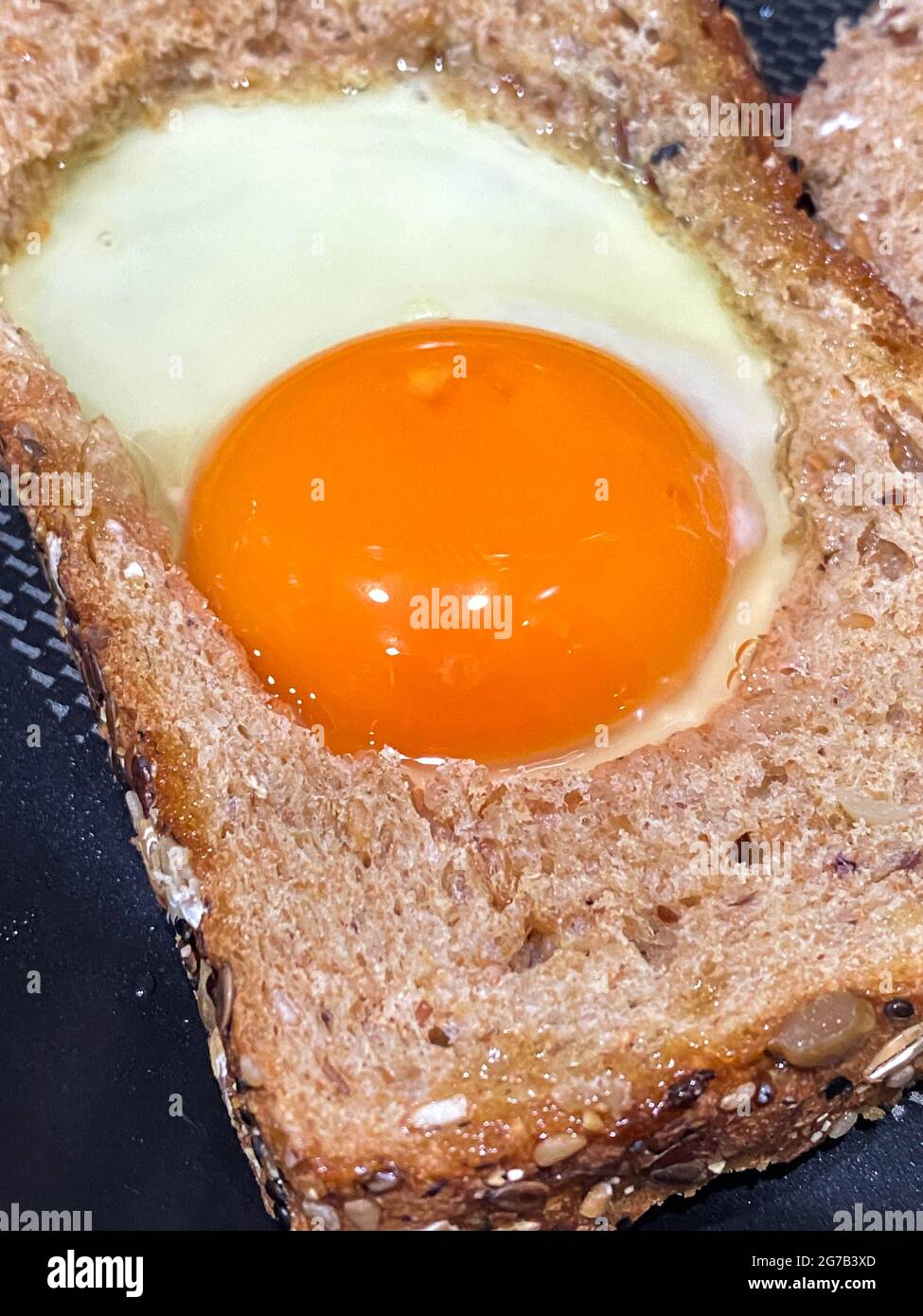 Egg inside a slice of wheat toast cooking for breakfast. Also known as ...