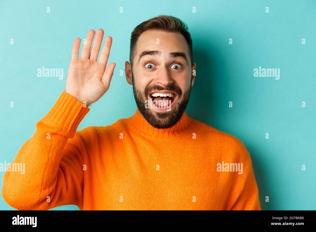 Handsome man waving hand to say hello, giving high five, standing over ...