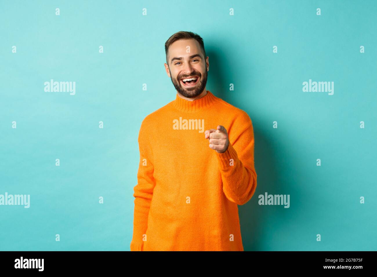 Handsome man laughing and pointing at camera, nodding in approval ...