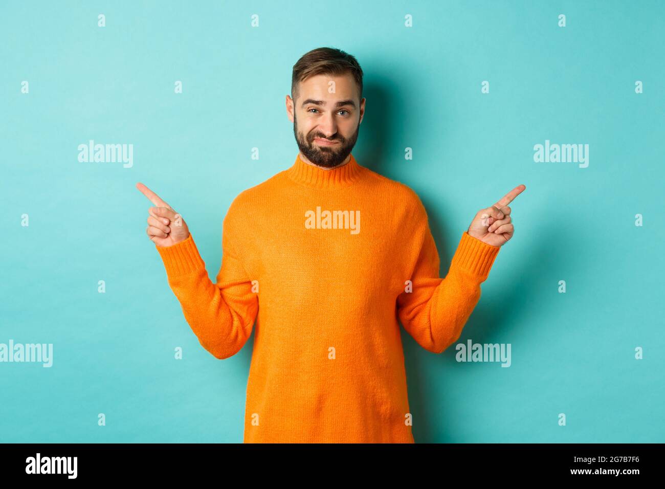 Doubtful and indecisive man pointing fingers sideways, showing ...