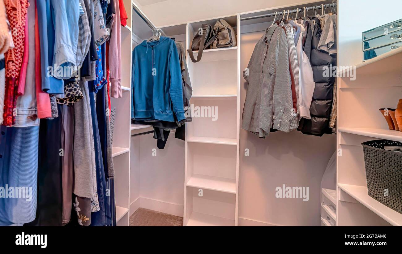 Pano Walk in closet with clothes on metal rods and built in storage ...