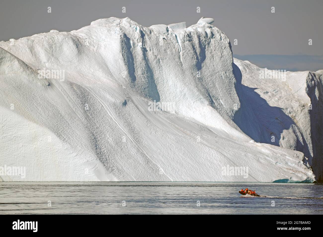 Small boat with passengers in front of huge iceberg, Disko Bay ...