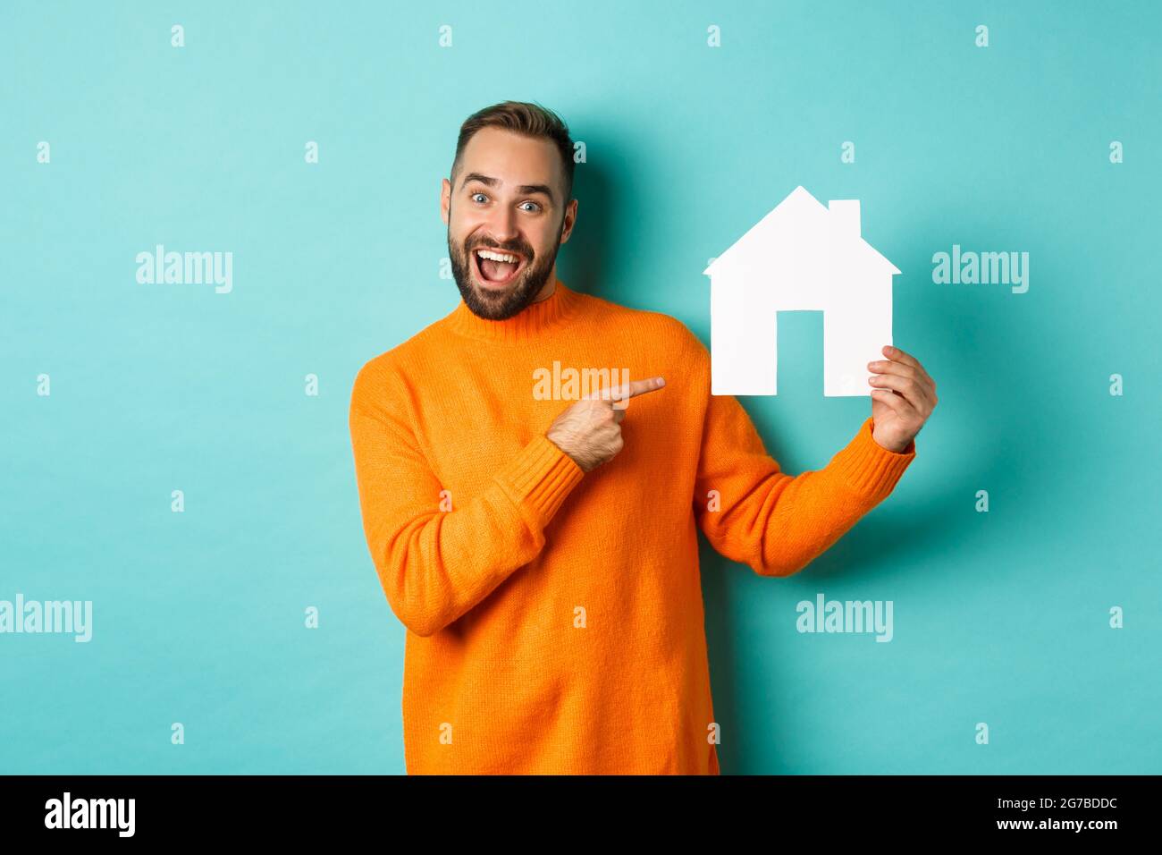 Real estate concept. Happy man pointing finger at paper home maket and ...