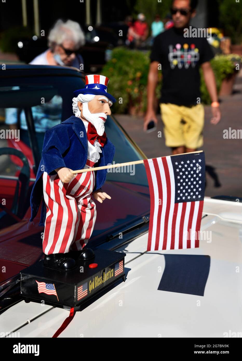 An Uncle Sam doll holding an American flag placed on the hood of a ...