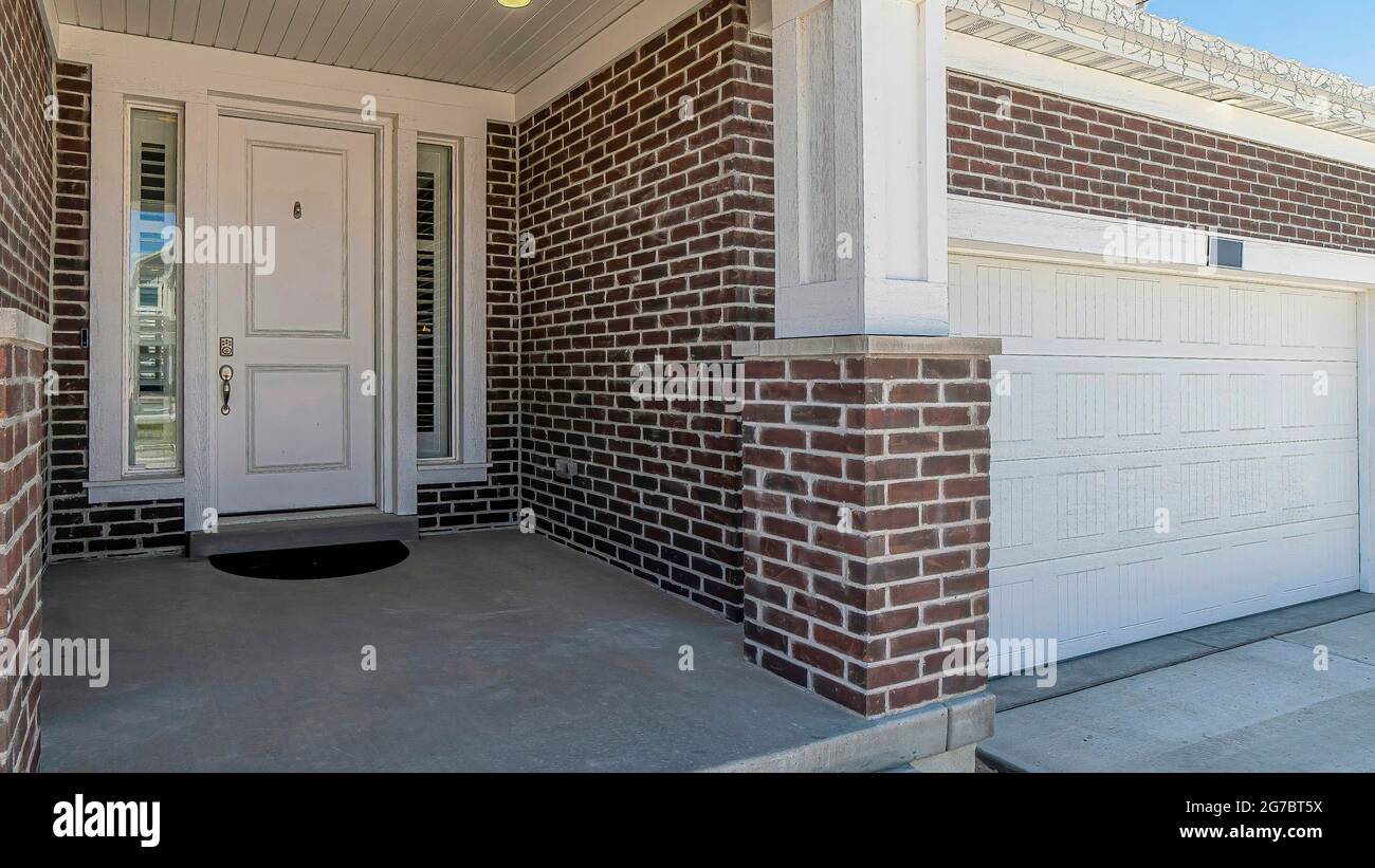 Pano Portico with white front door adjacent to the garage door at the ...