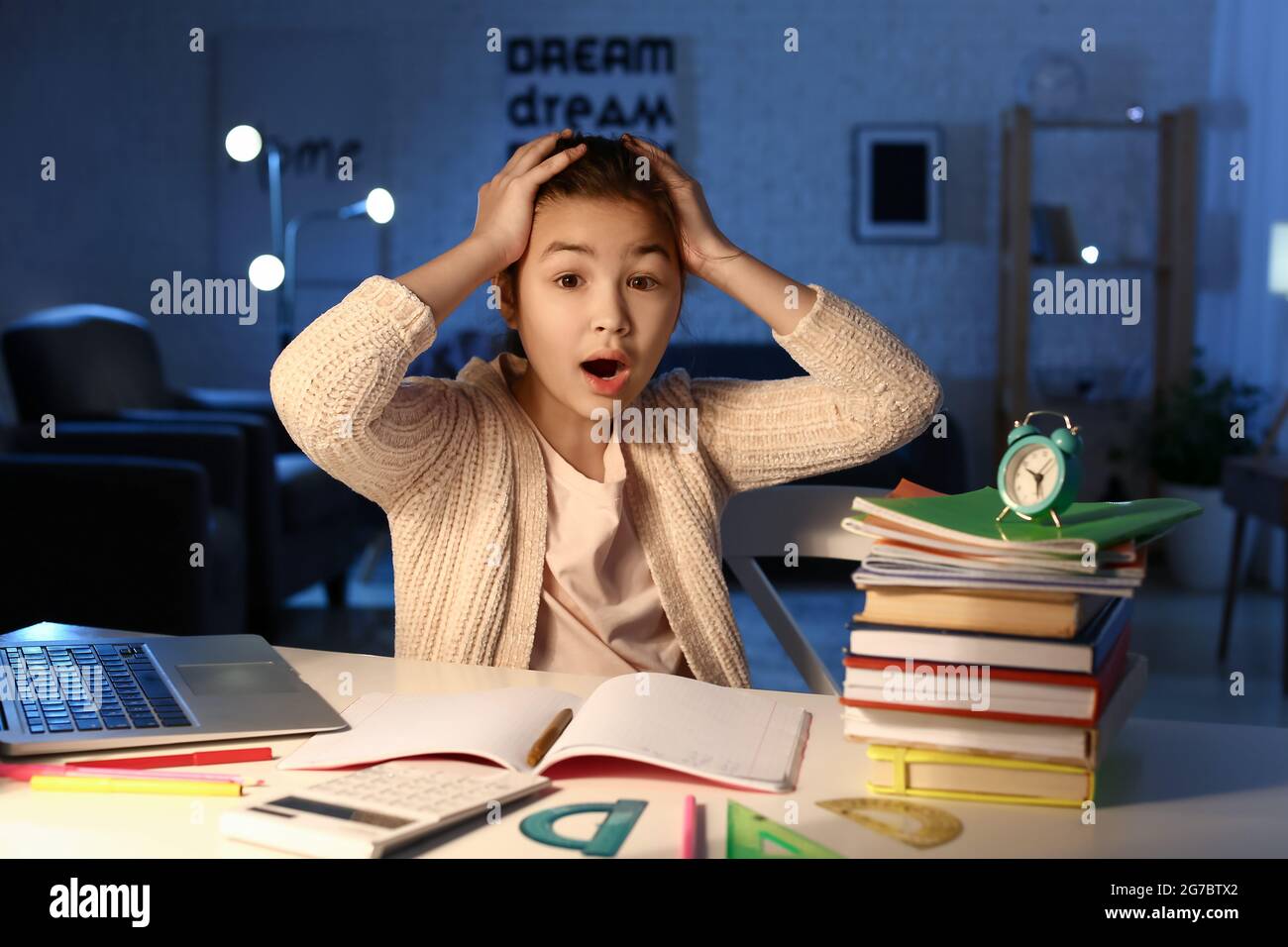 Shocked little girl doing homework at home late in evening Stock Photo ...