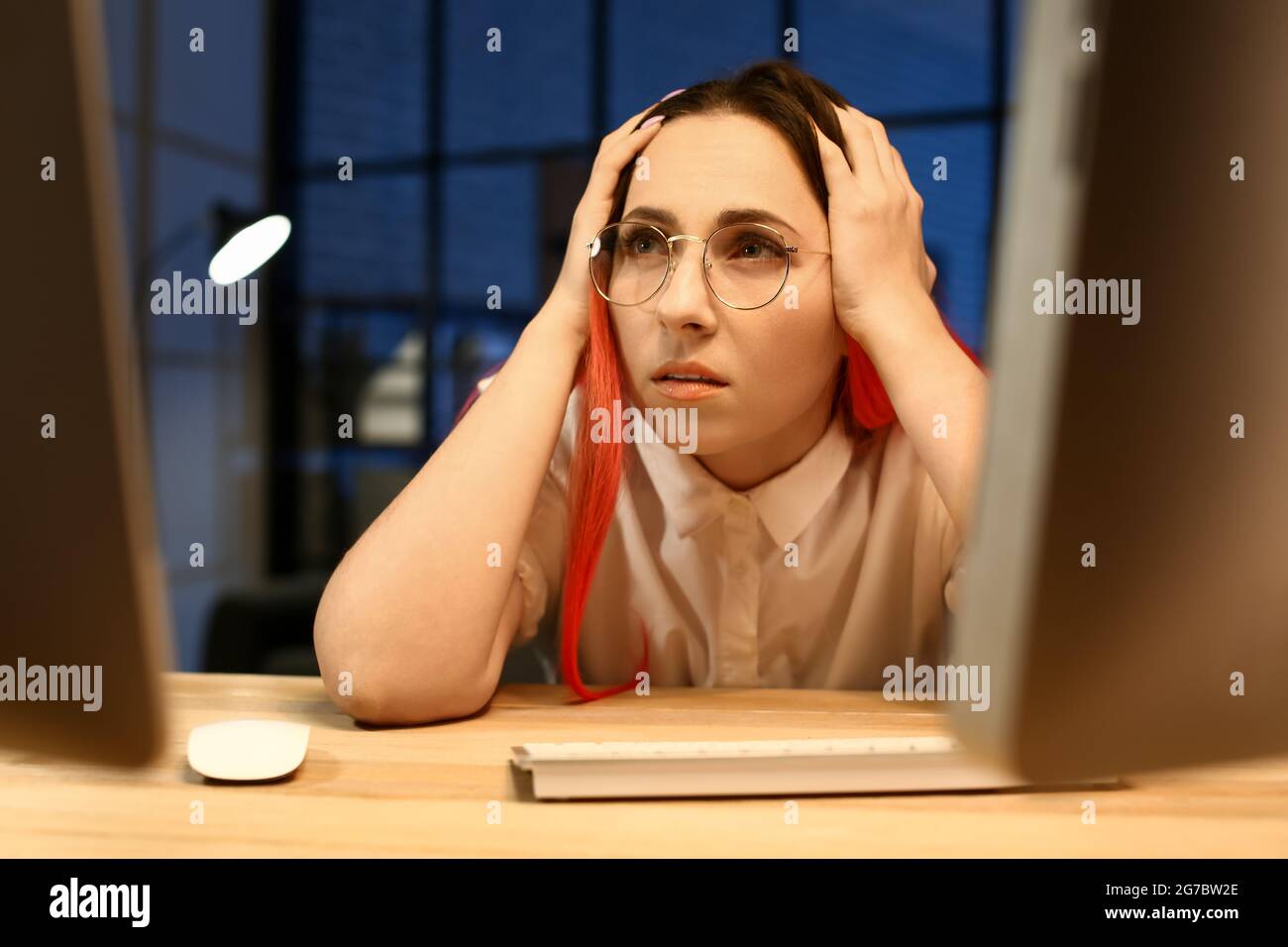 Stressed female programmer working with computer in office at night ...