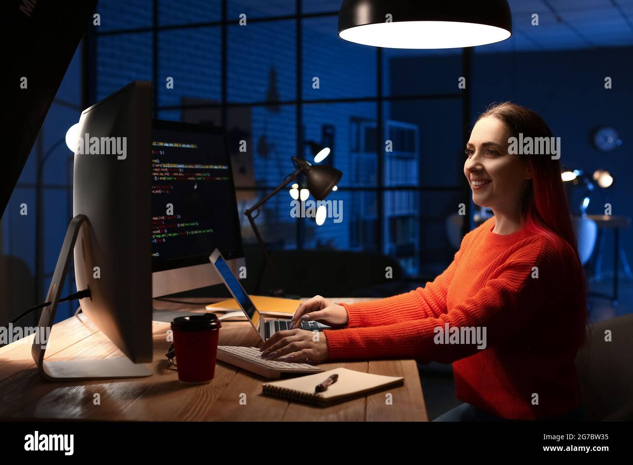 Female programmer working with computer in office at night Stock Photo ...