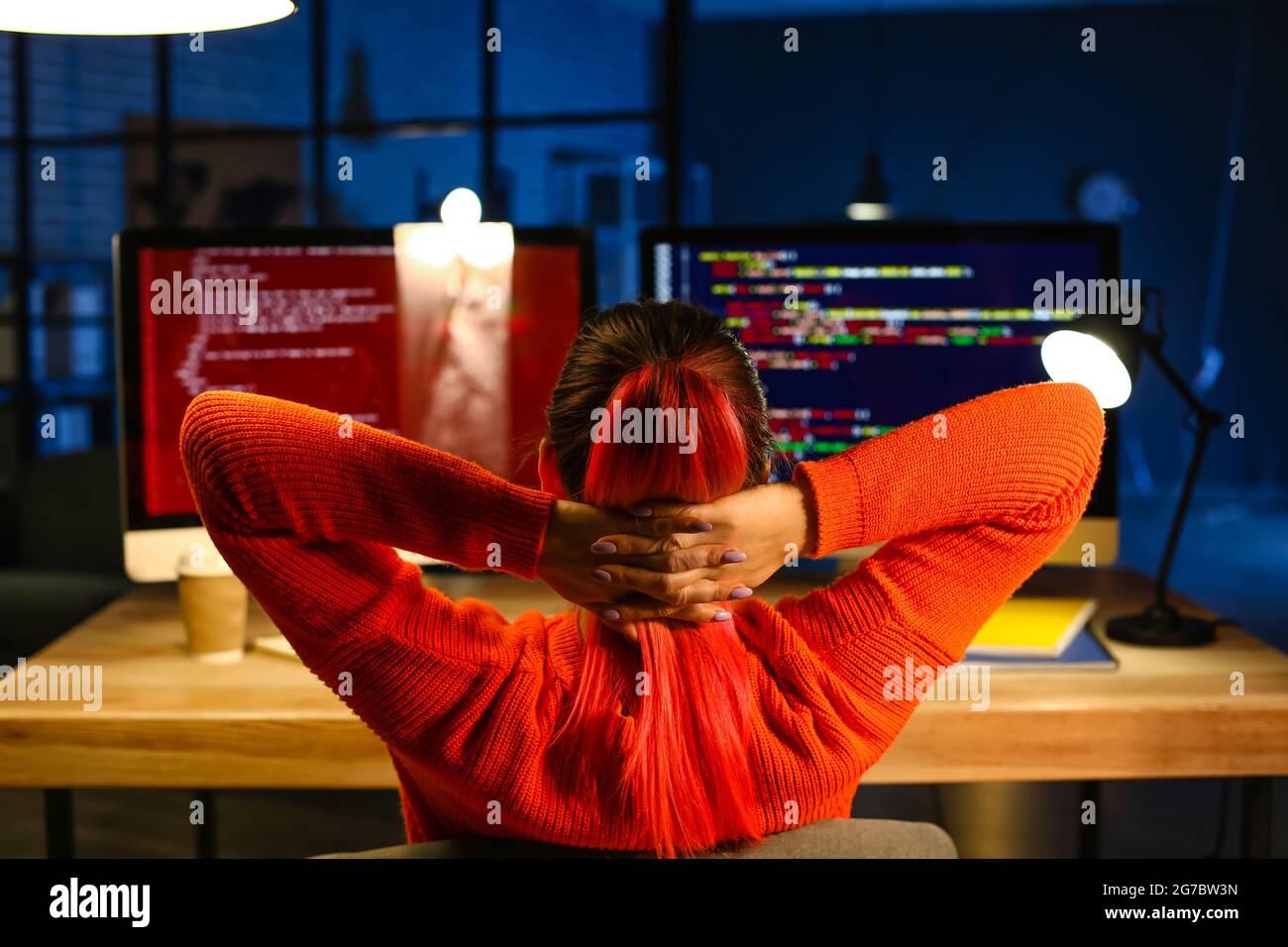 Female programmer relaxing in office at night Stock Photo - Alamy