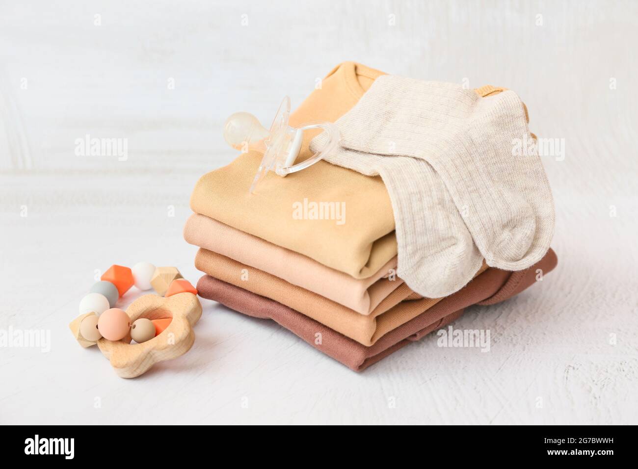 Stack of baby clothes, pacifier and teether on light background Stock ...