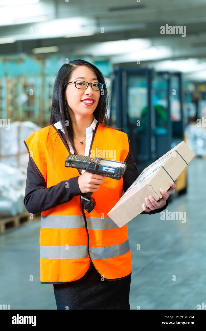 Logistics - female worker or shipper with protective vest and scanner ...