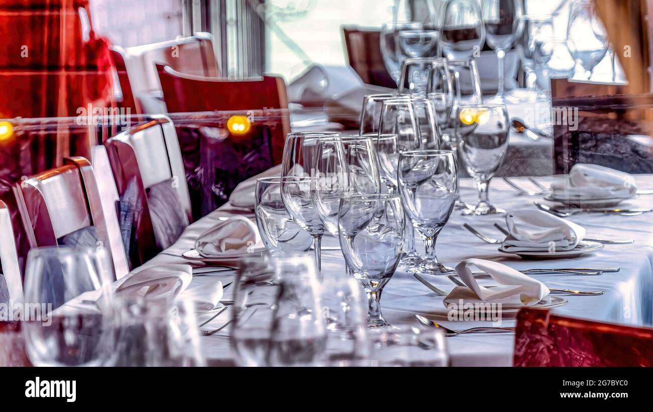 Pano Dinner table setting with wine glasses and tableware seen through ...