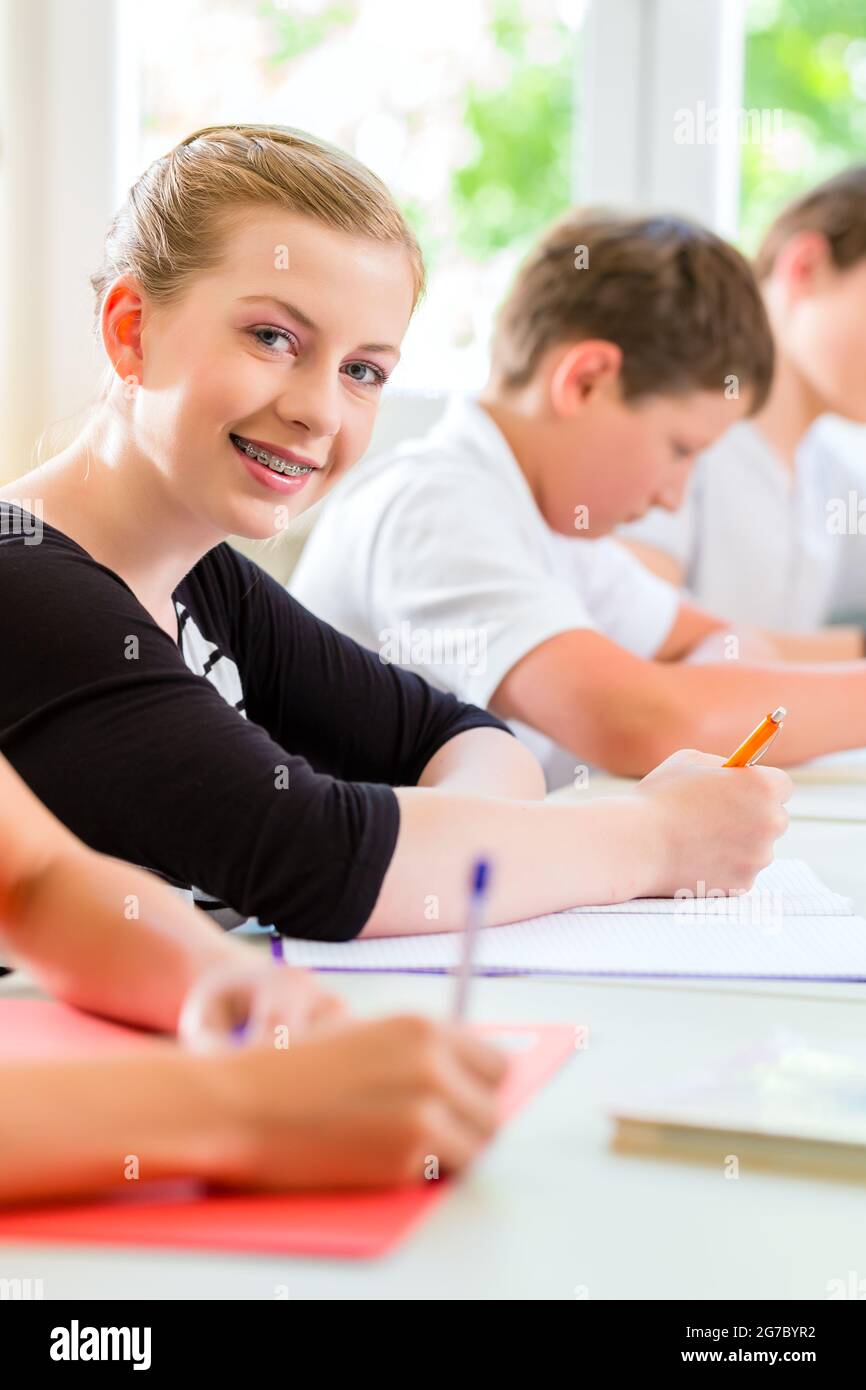 Students or pupils of school class writing an exam test in classroom ...