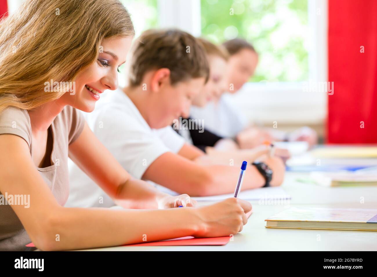 Students or pupils of school class writing an exam test in classroom ...