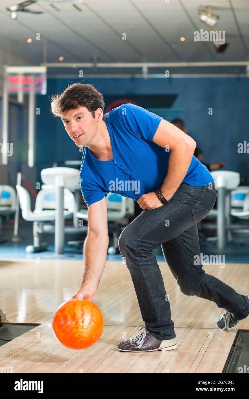 Young man in bowling alley having fun, the sporty man playing a bowling ...
