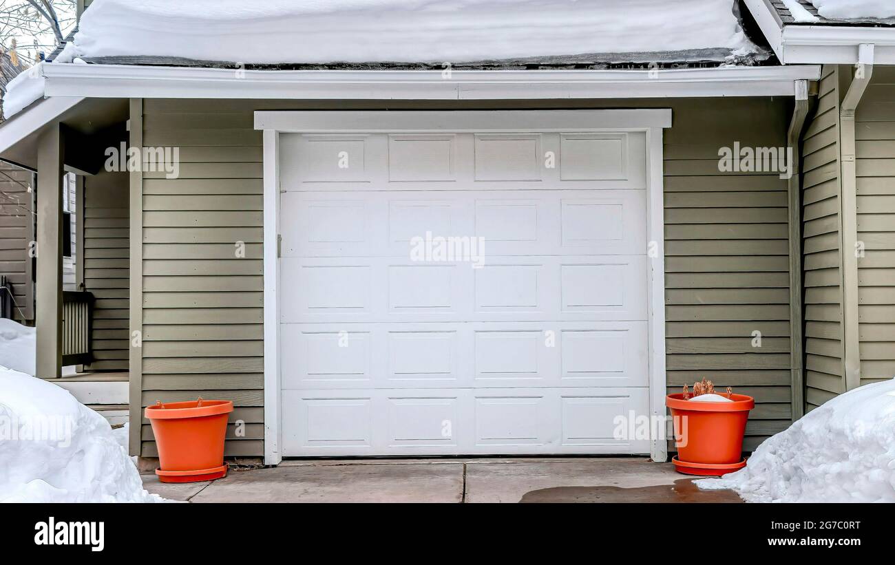 Pano Snowy driveway and yard in winter in front of attached two car ...