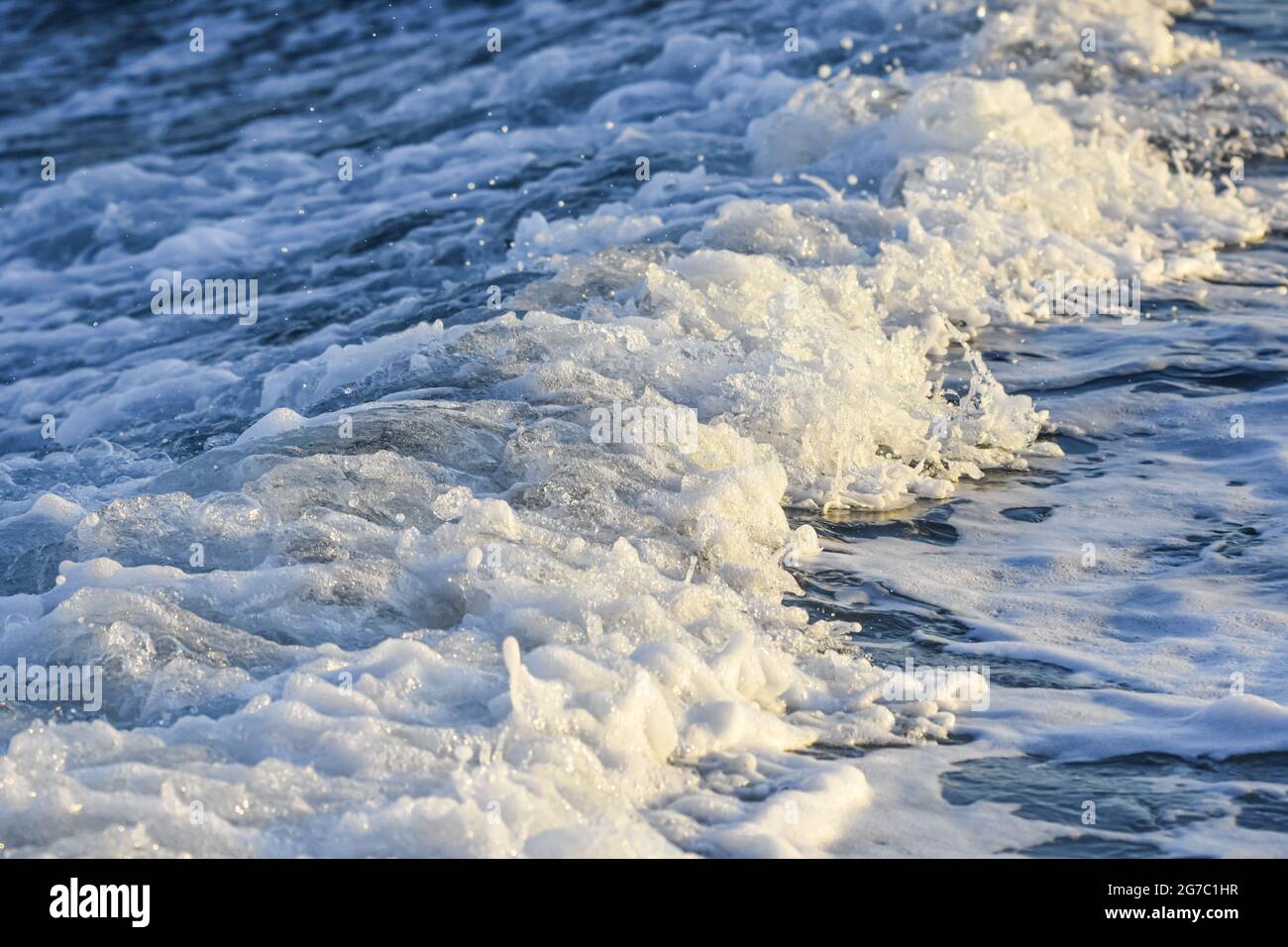 Seawater churned to a froth in the wake of a large ship. Late afternoon ...