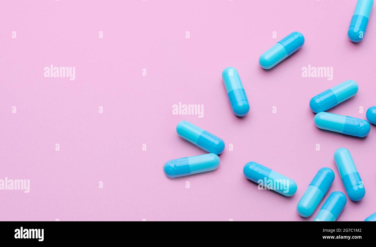 Blue antibiotic capsule pills spread on pink background. Antibiotic ...
